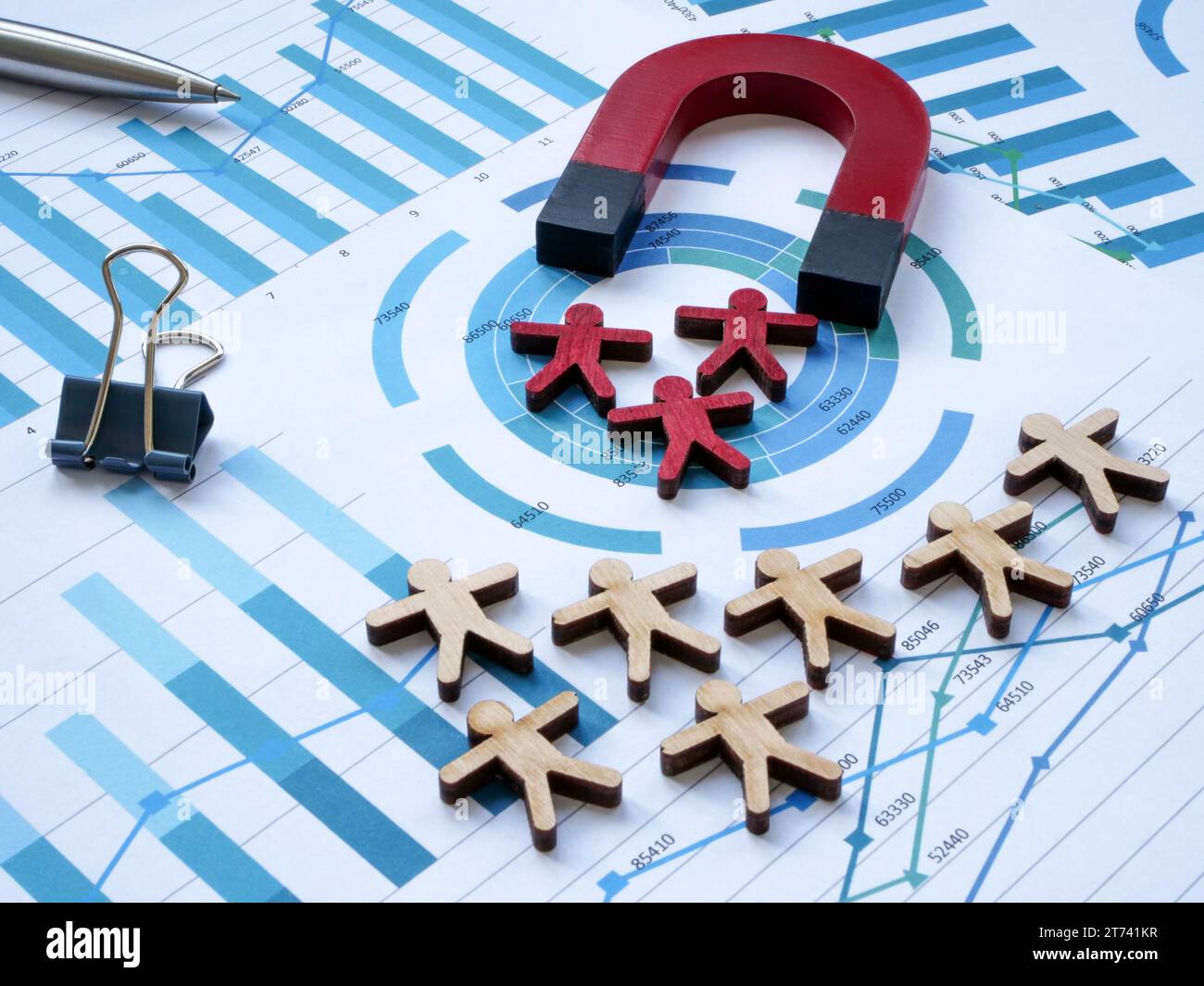 Magnet and figures of customers or employees on charts Stock Photo - Alamy