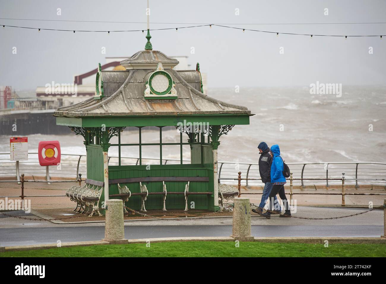 Couple in waterproof clothes walking along Blackpool seafront during ...