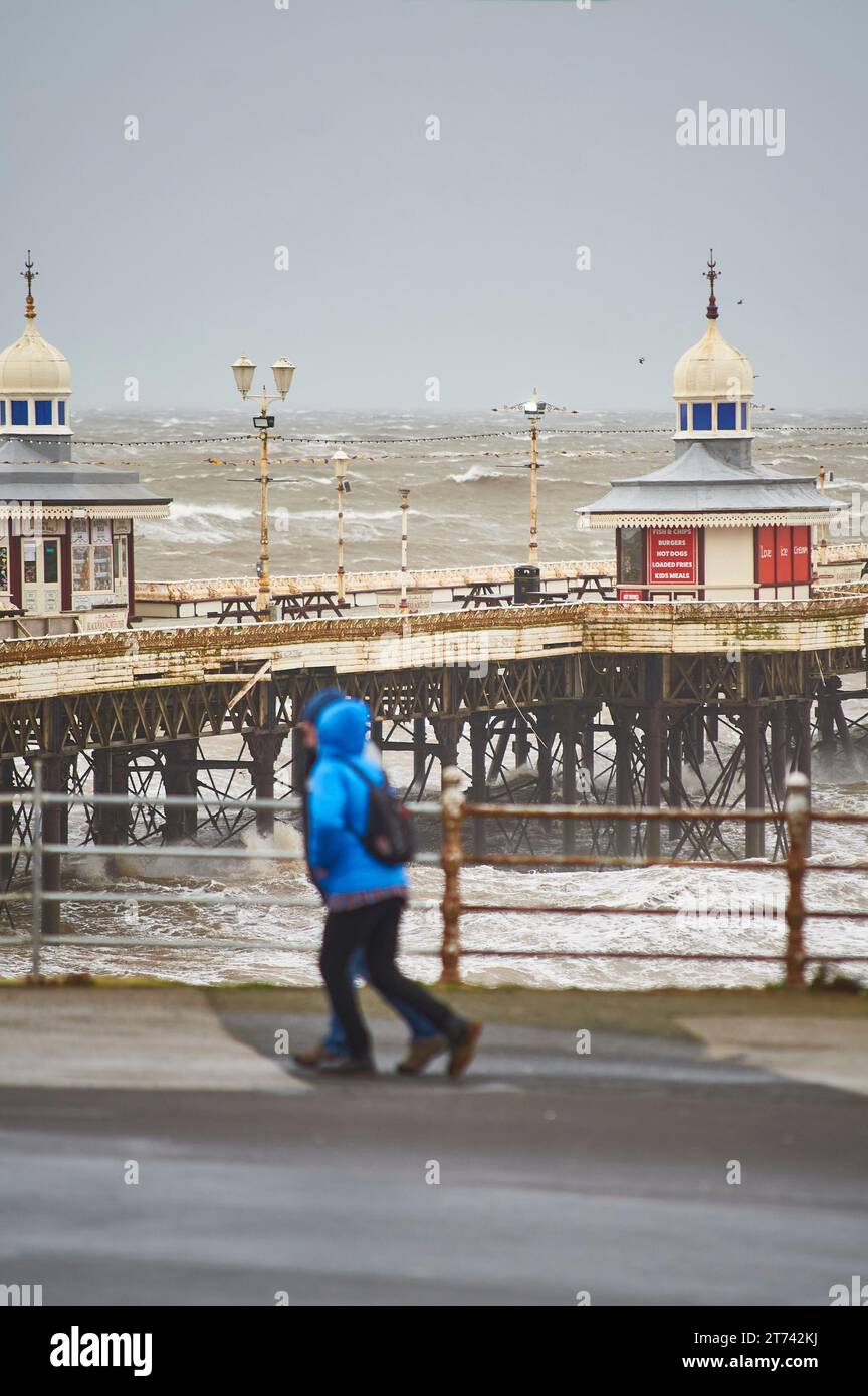 Couple in waterproof clothes walking along Blackpool seafront during ...