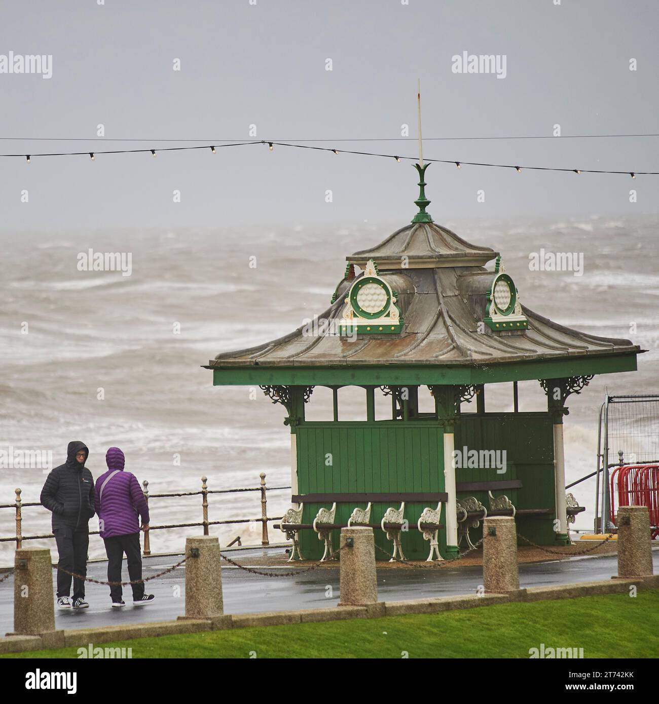 Couple in waterproof clothes walking along Blackpool seafront during ...