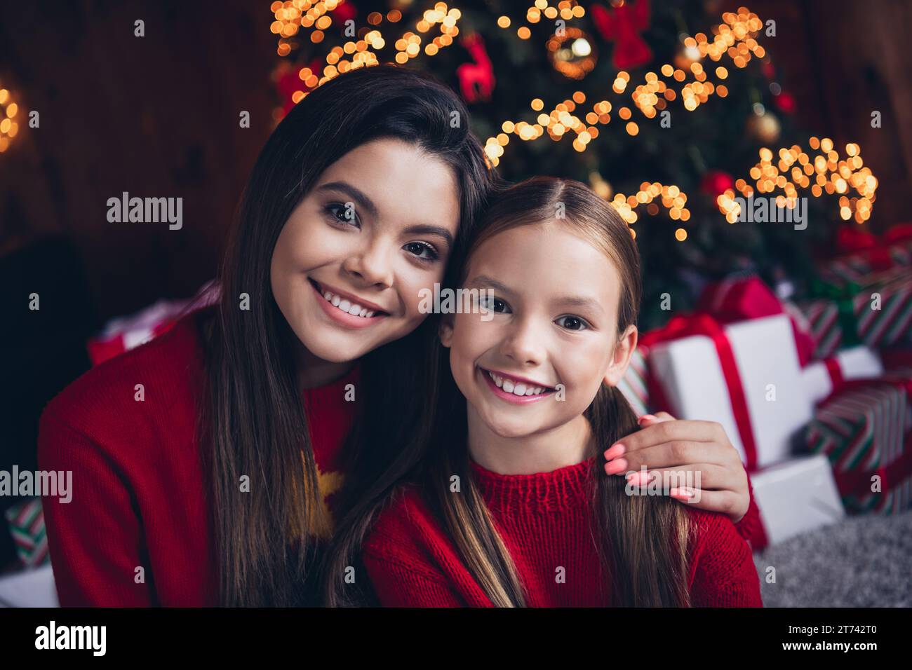 Photo of sweet adorable small sisters wear red jumpers embracing ...