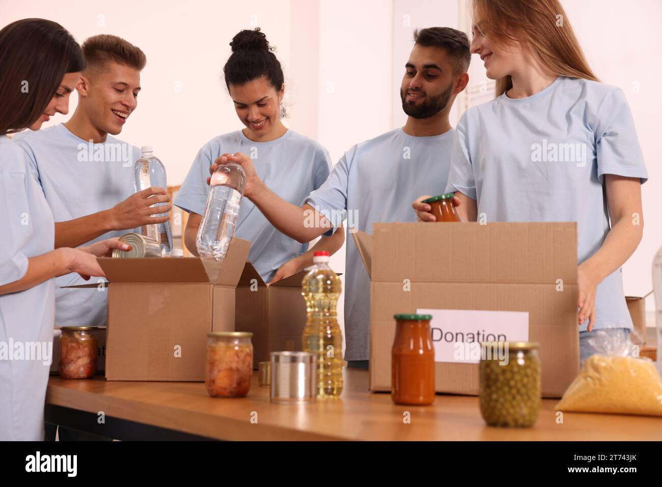 Group of volunteers packing food products in warehouse Stock Photo - Alamy