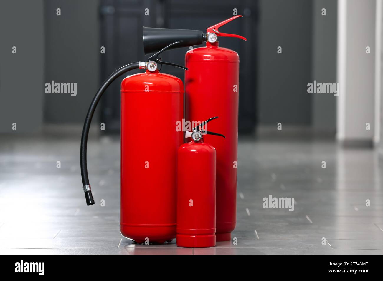 Three new red fire extinguishers in hall Stock Photo - Alamy