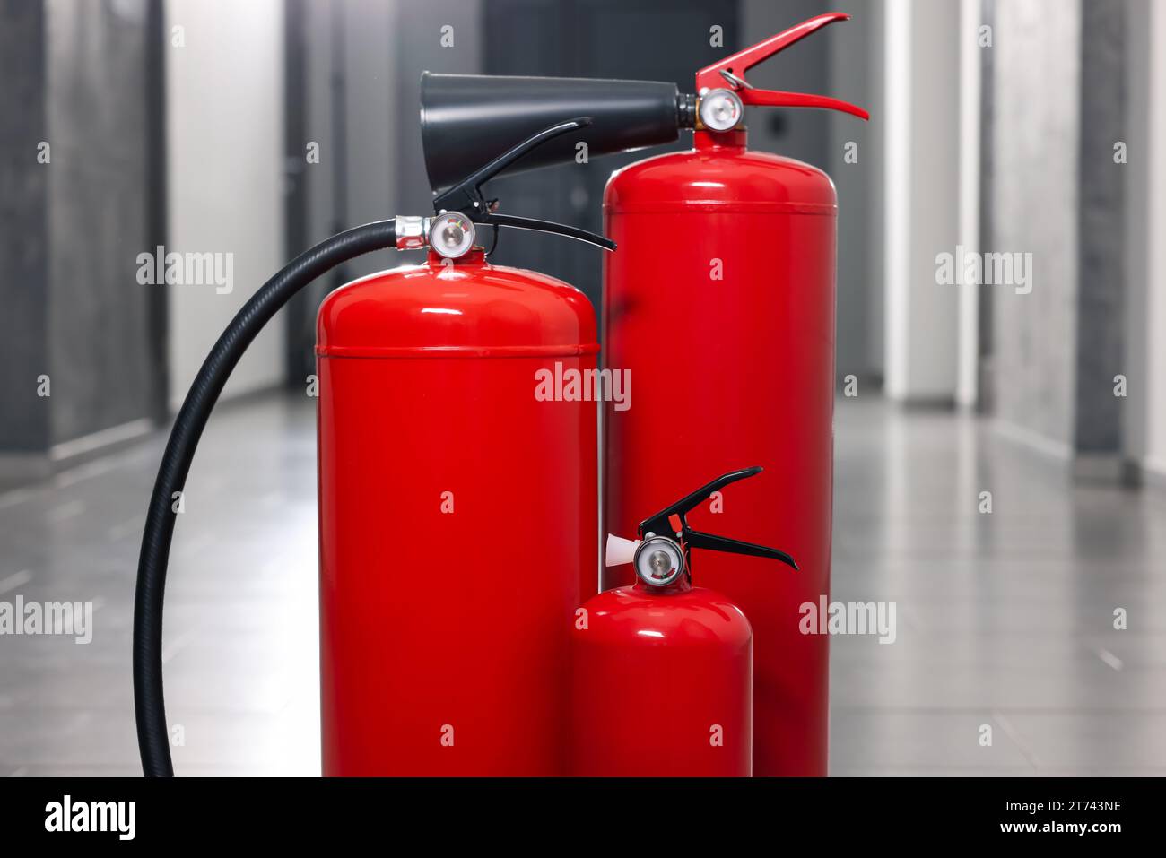 Three red fire extinguishers in hall, closeup Stock Photo - Alamy