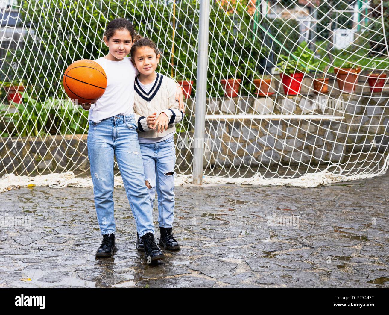 Two girls hugging each other after playing basketball in the backyard ...