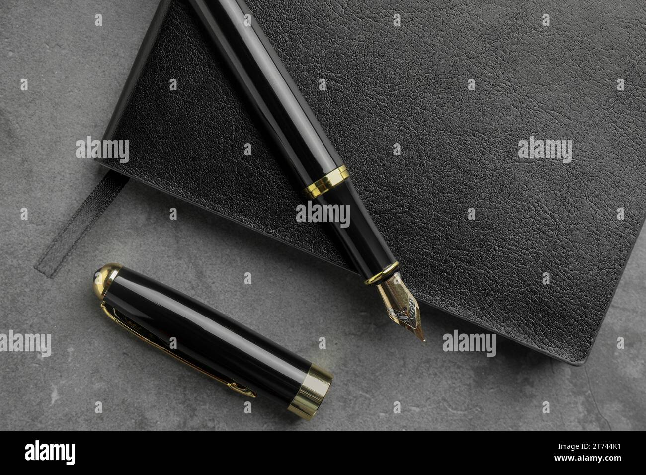 Stylish fountain pen, cap and leather notebook on light grey textured ...