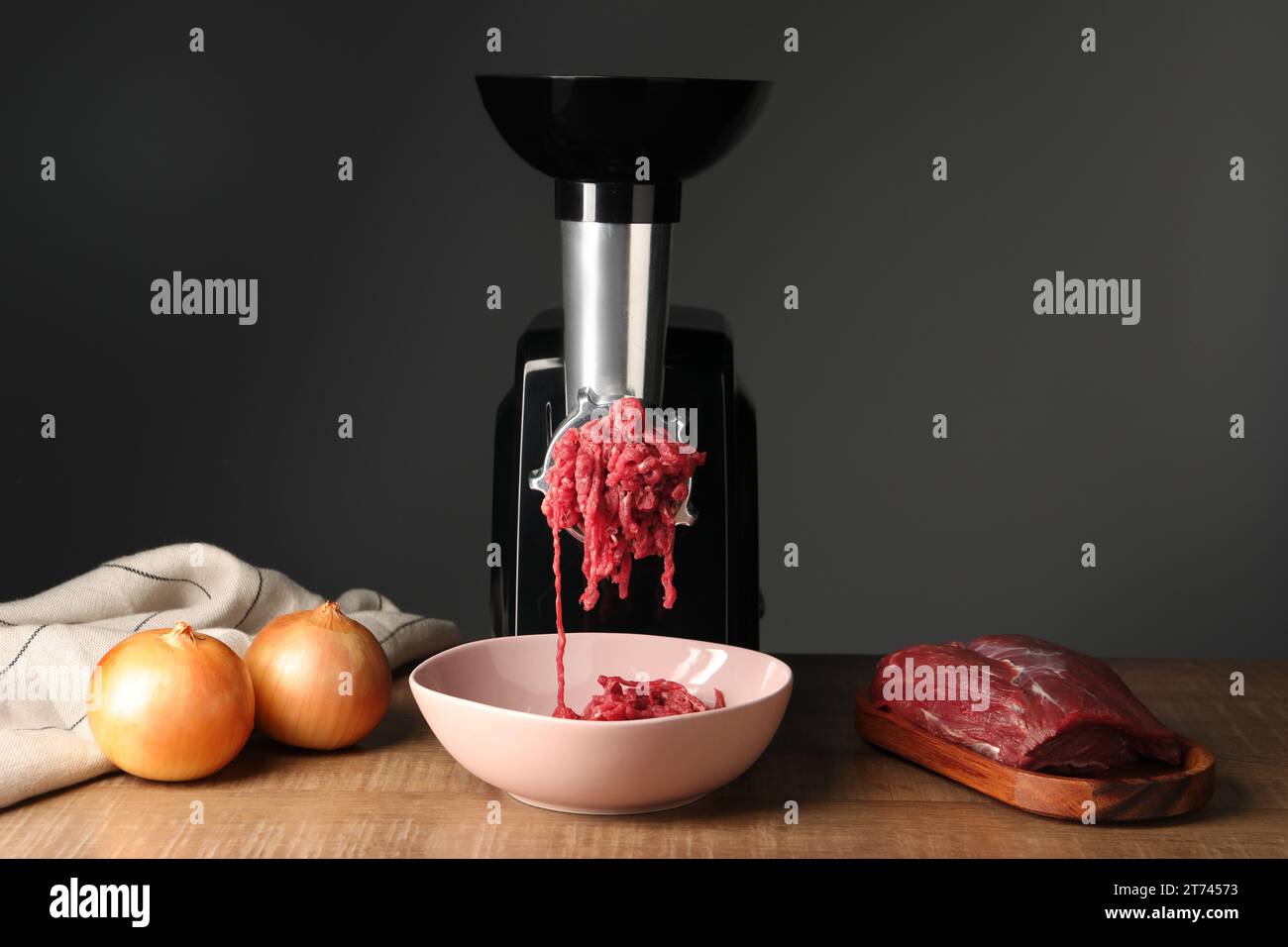 Electric meat grinder with beef mince and onion on wooden table against ...