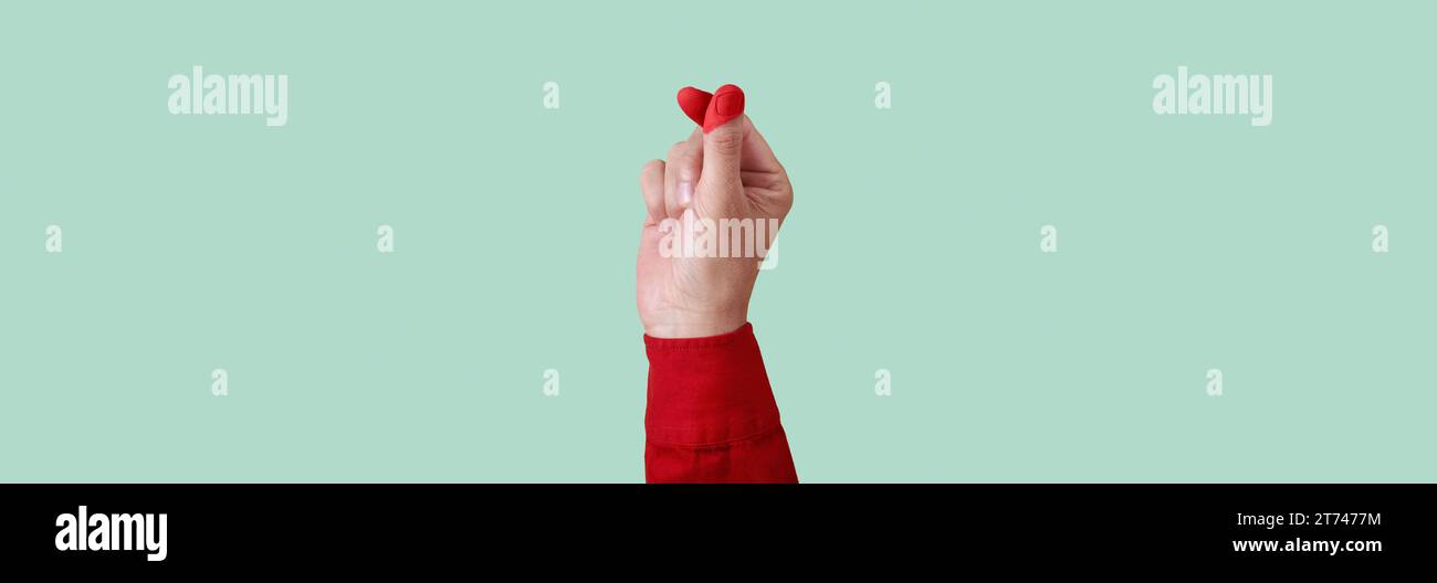 man, wearing a red shirt, doing the finger heart gesture, with his ...