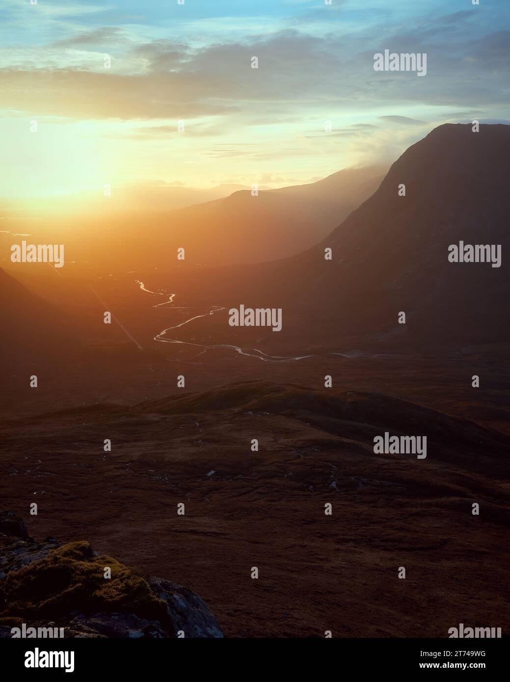 A winding road between mountain ranges illuminated by the rising sun ...