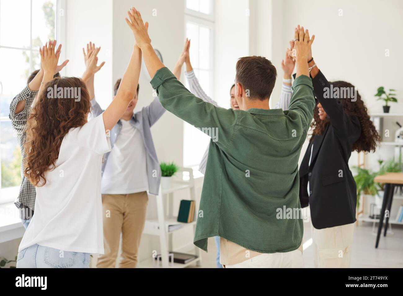 Young people friends standing in a circle raising arms up holding hands ...