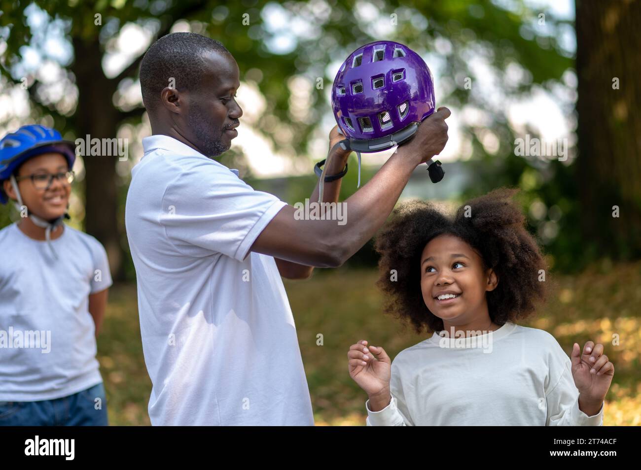 Dad fixing a protective hemlet on his kids head Stock Photo - Alamy