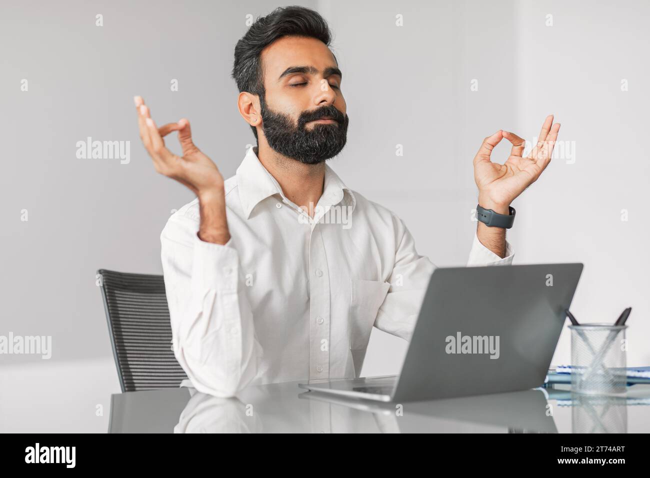 Indian businessman meditating at office desk Stock Photo - Alamy