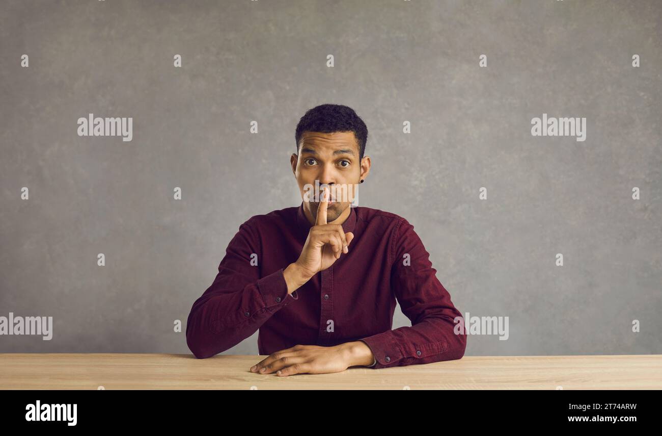 Portrait of young black man doing shush gesture and asking you to keep ...