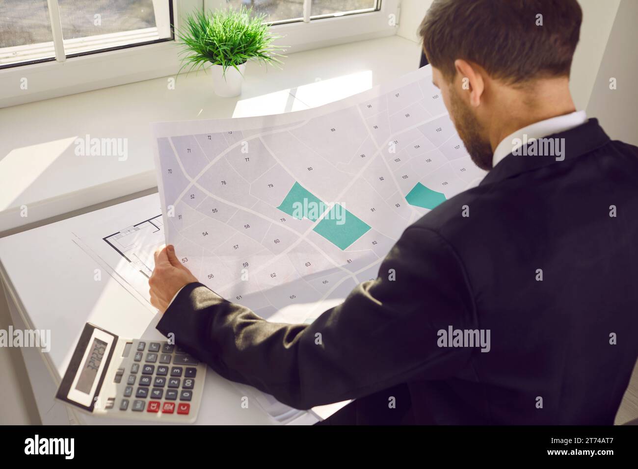 Male professional engineer analyzing cadastral map in office Stock ...