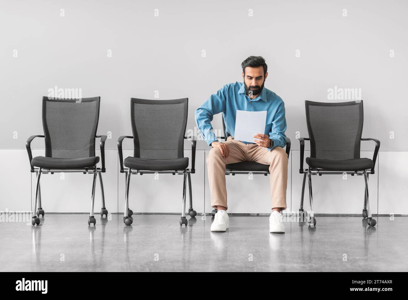 Indian man reviewing documents in waiting area Stock Photo - Alamy