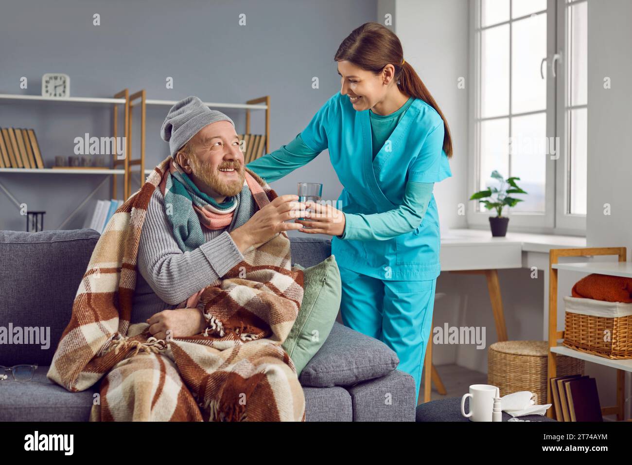 Smiling nurse caring about elderly unwell patient at home Stock Photo ...