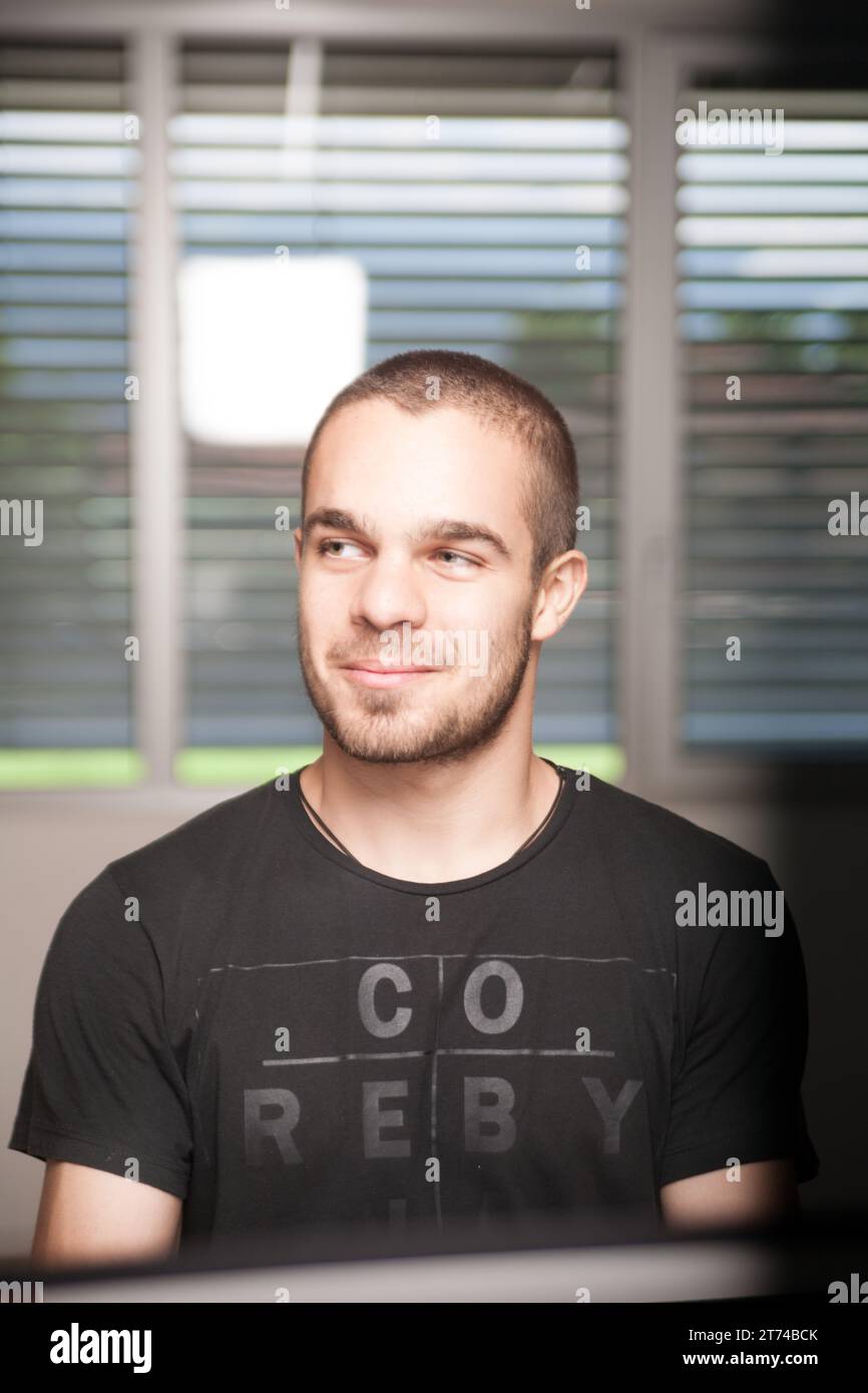 Young man with very short hair and stubble, smiling at staff while ...