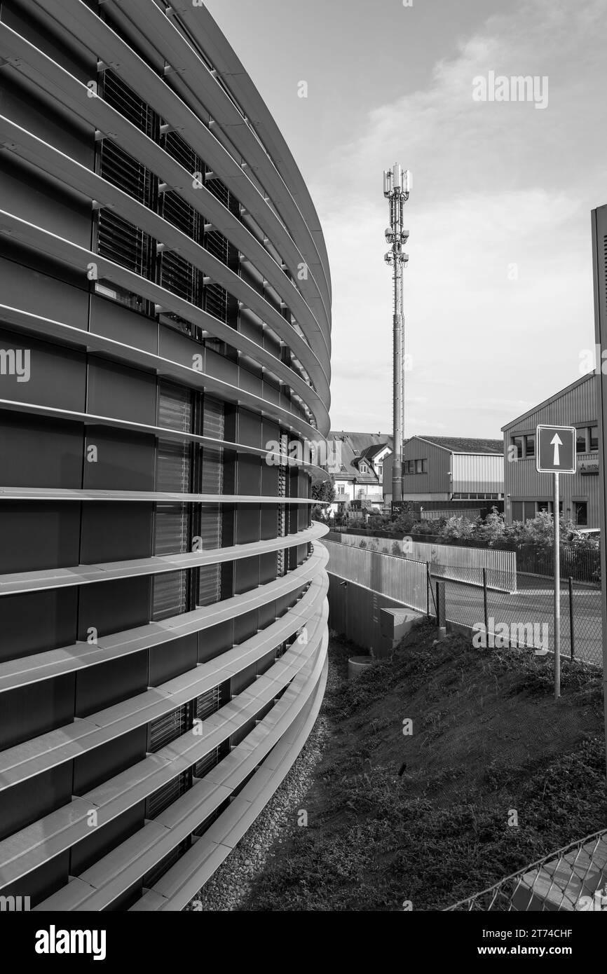 A circular shaped building is situated on the side of a grassy hill ...