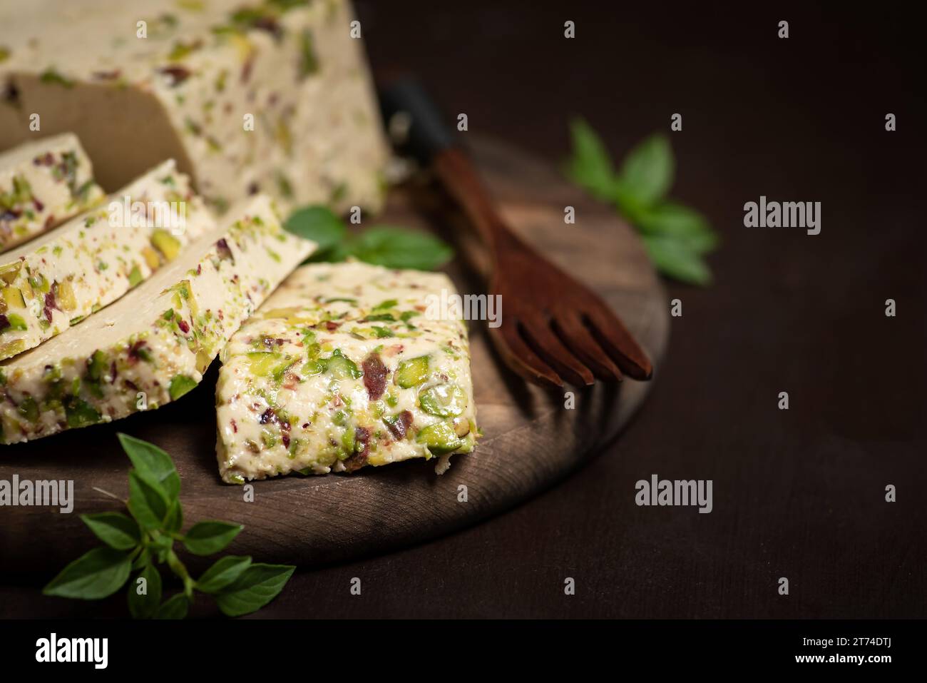 Sliced turkish halva with pistachio on a wooden plate and rustic ...