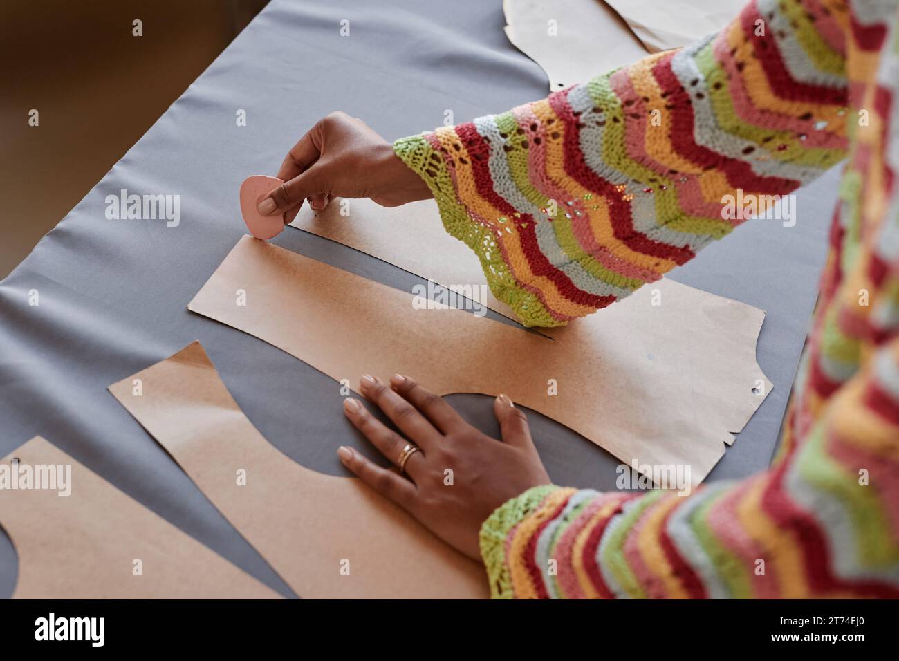 Above angle of hands of young seamstress contouring sewing paper ...