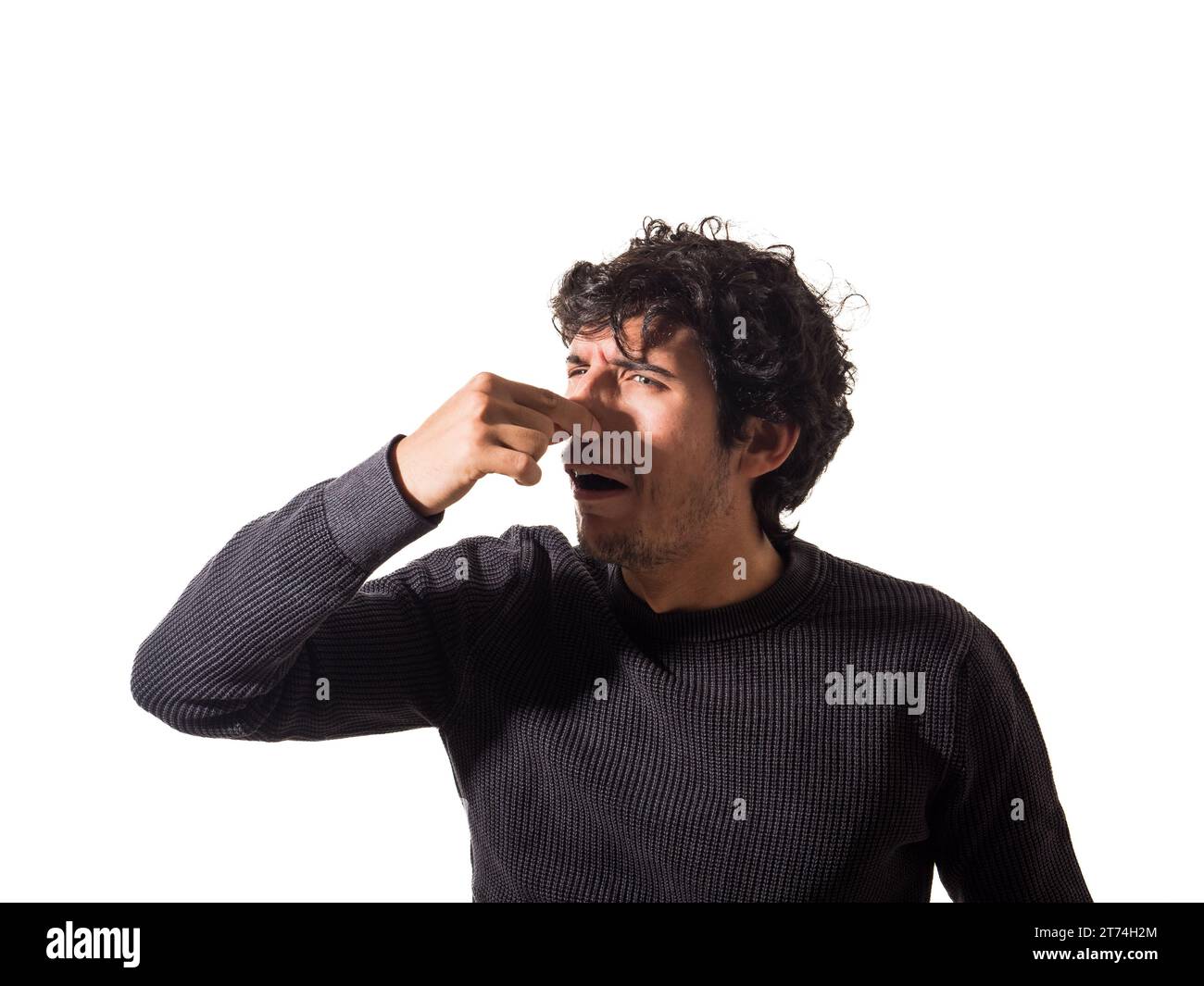 A man making a funny face with his finger, closing his nose because of ...