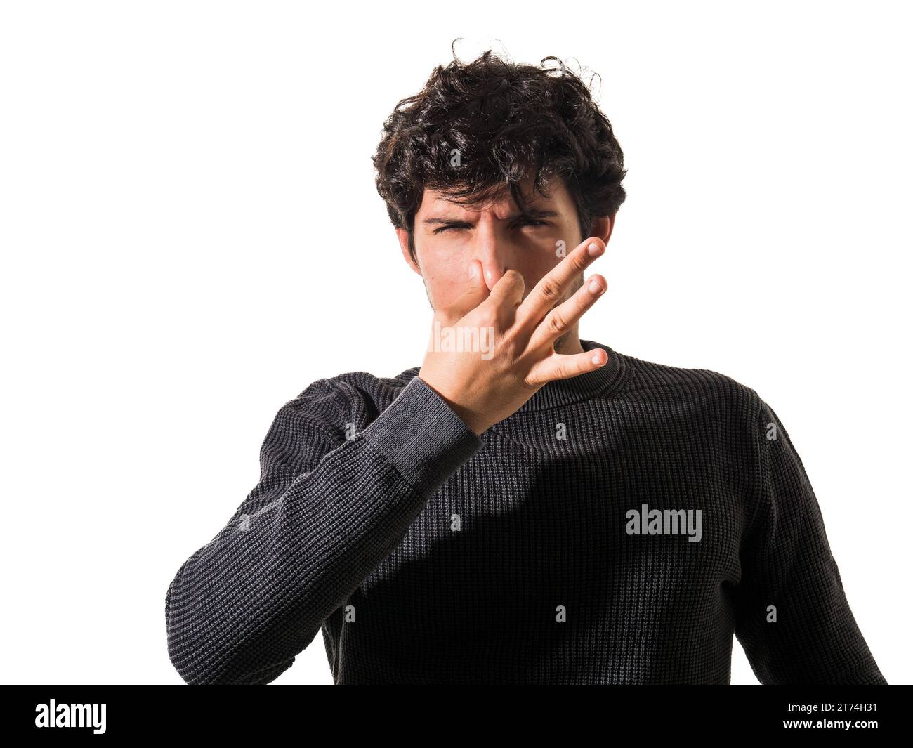 A man making a funny face with his finger, closing his nose because of ...