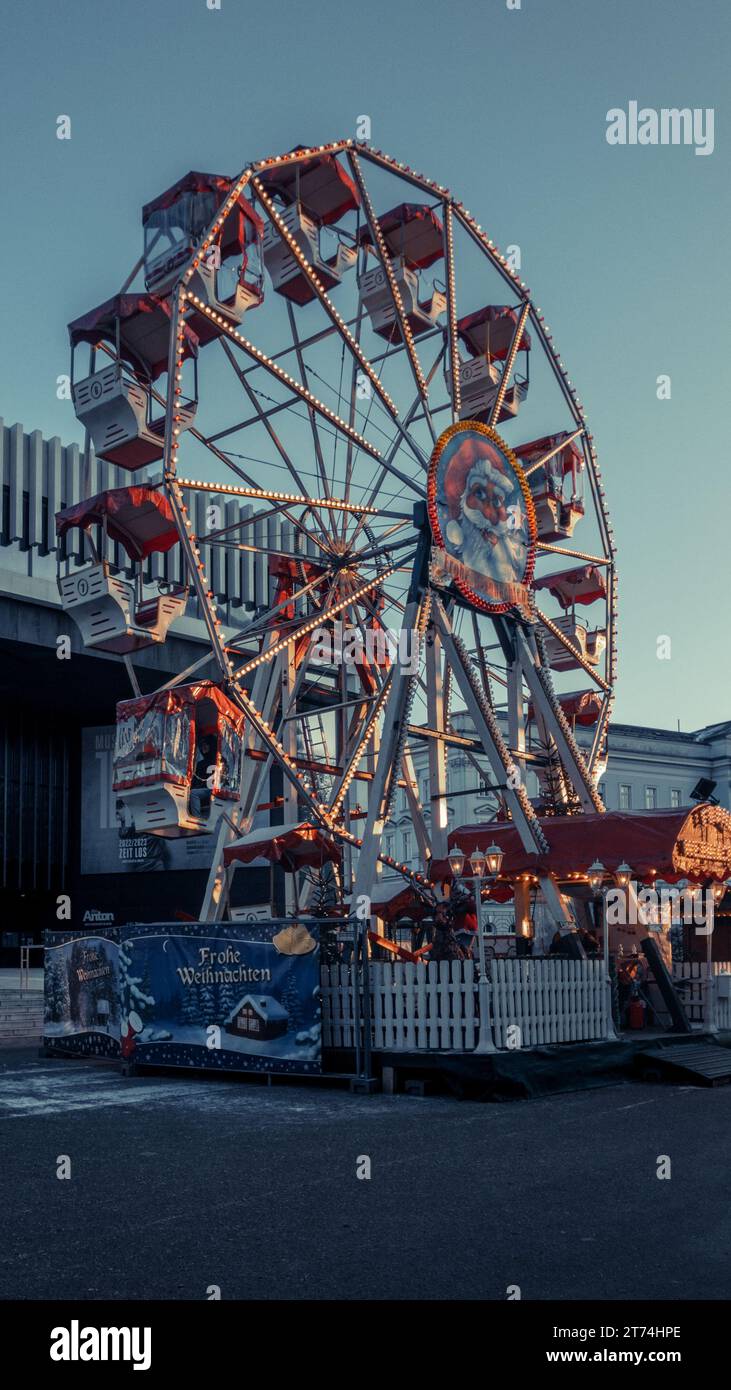 A Ferris wheel stands in a deserted lot near a building with a sign ...