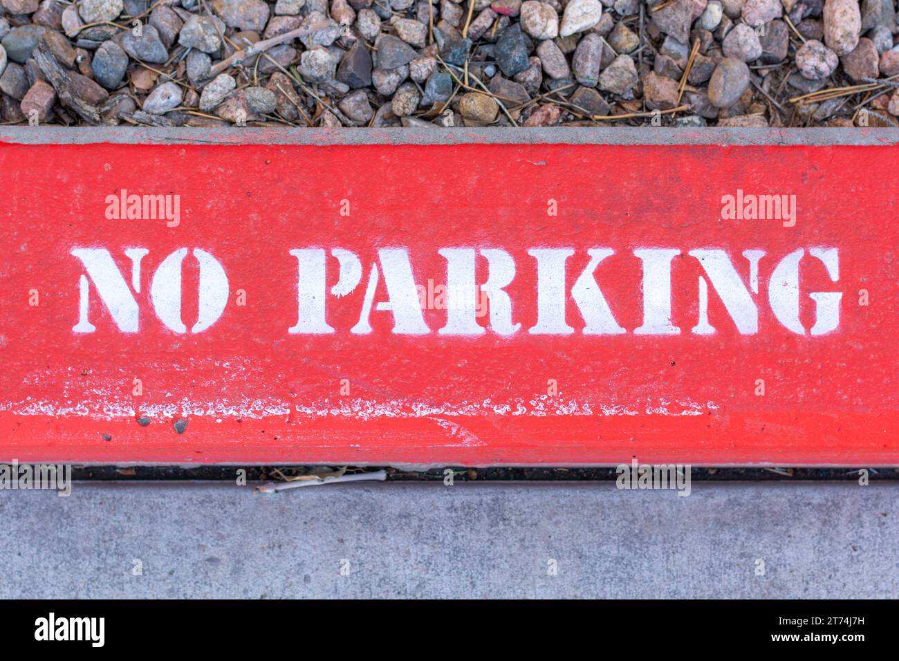 Close up of a red "No Parking" sign with white lettering painted onto a ...