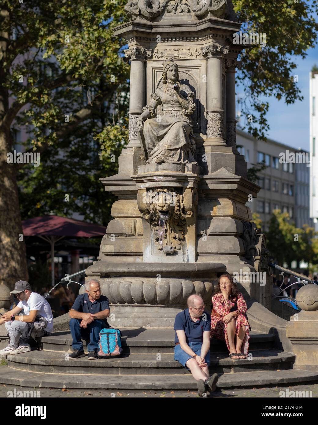People sitting around a historical monument in Cologne old town Stock ...