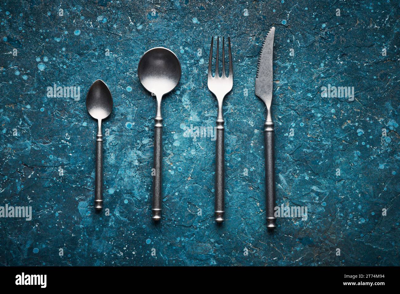 Dark blue old vintage backdrop with kitchen utensils fork, knife, spoon ...