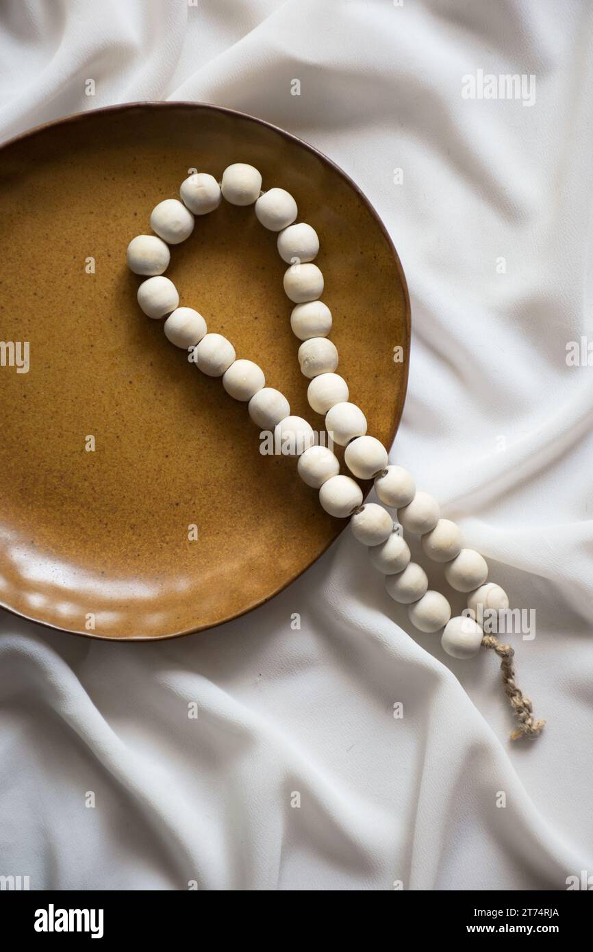 A small gold plate is adorned with wooden beads, creating a decorative ...