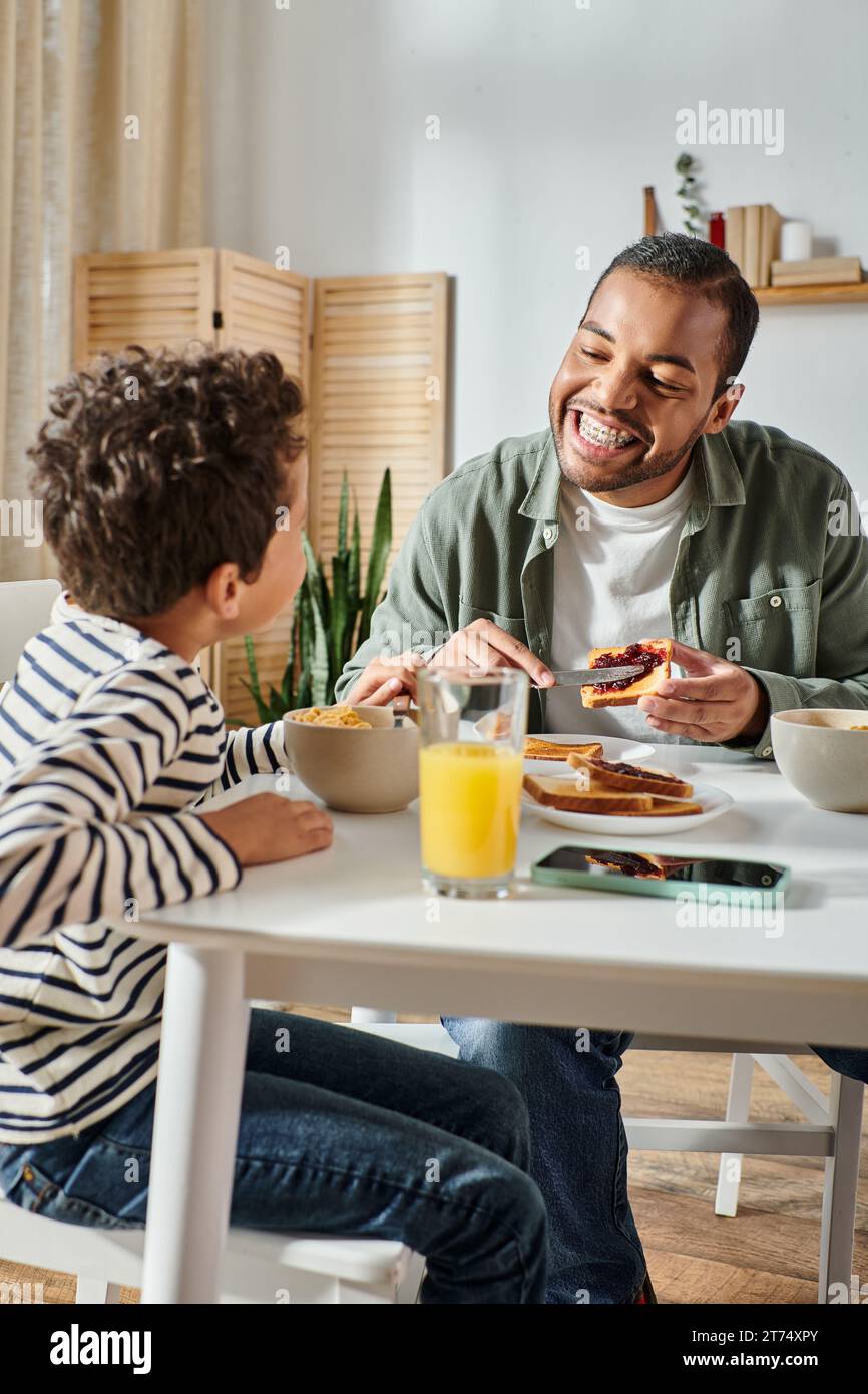 vertical shot of happy african american boy smiling to his father while ...