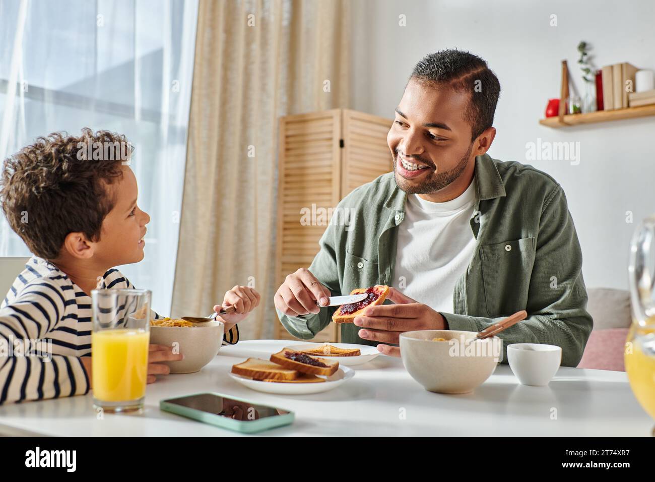 good looking african american father spreading jam on toast and smiling ...