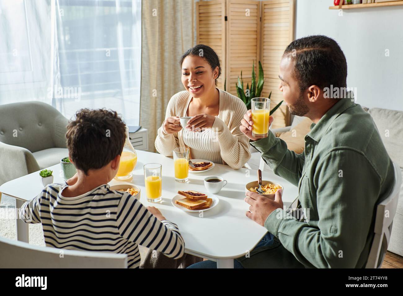 cheerful modern african american family having breakfast together and ...