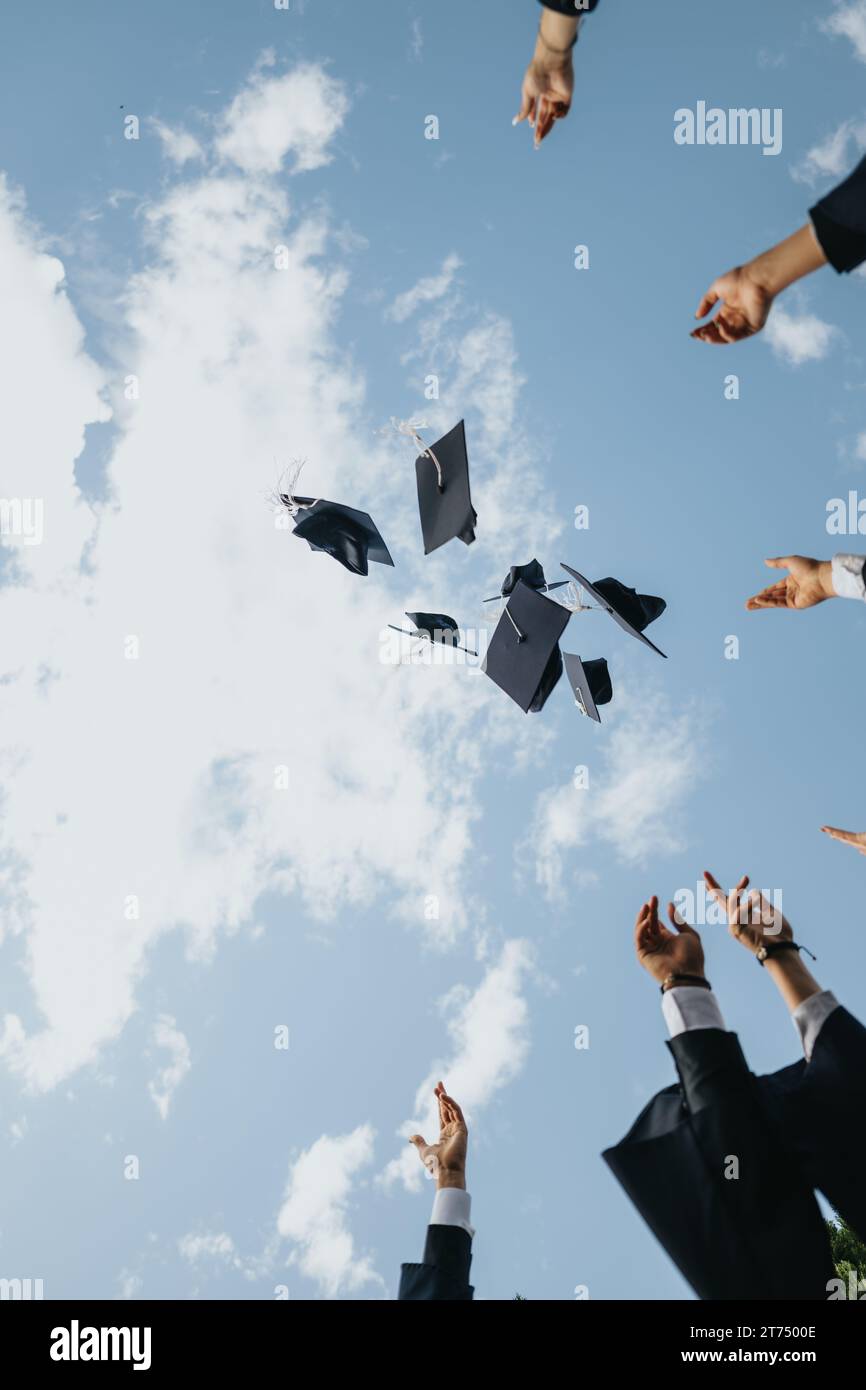 University students throwing caps in the air after successful ...