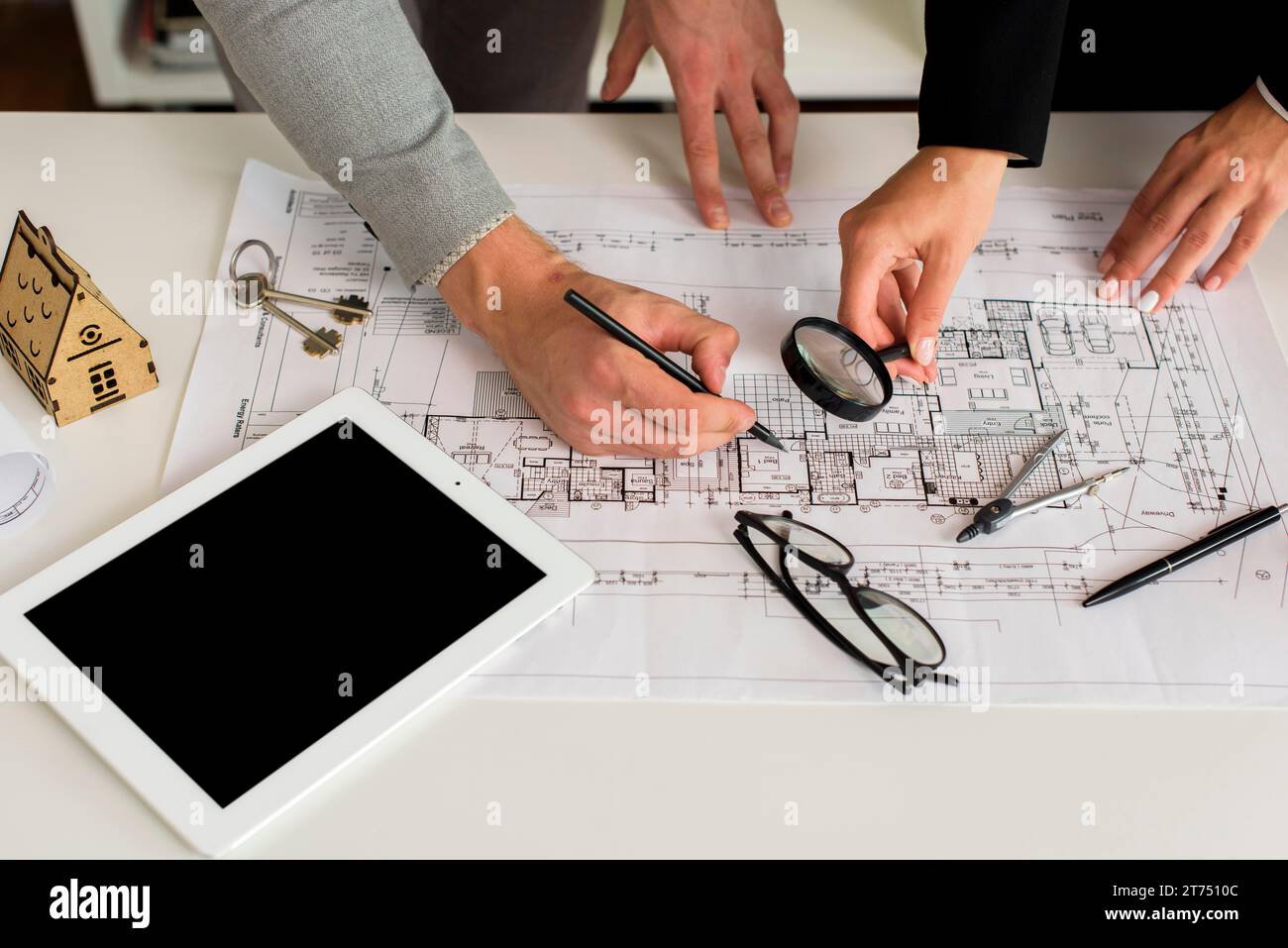Architects analysing plan with magnifier Stock Photo - Alamy