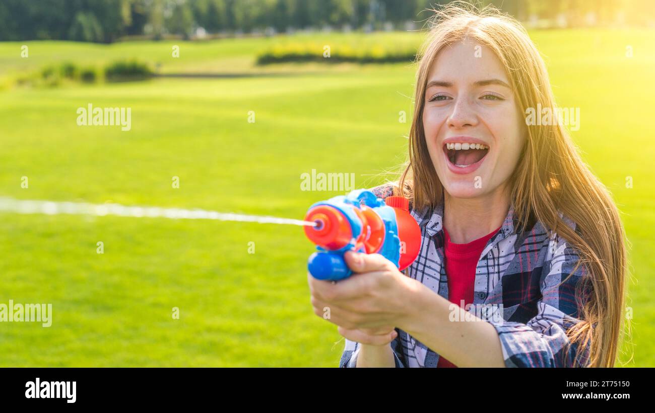 Blonde girl playing with water gun Stock Photo - Alamy