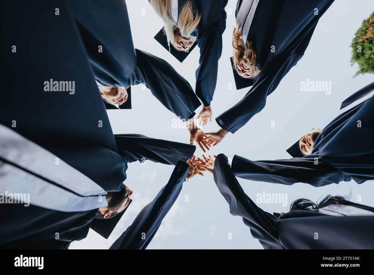 Group of graduated students putting their hands together outdoors after ...