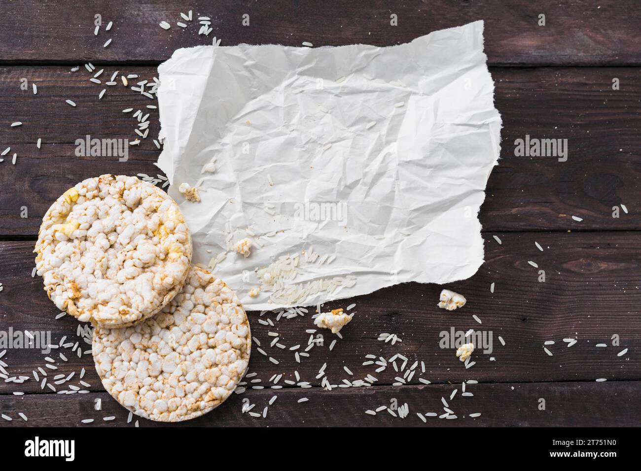 Crumpled paper with two round puffed rice cake with grains wooden desk ...