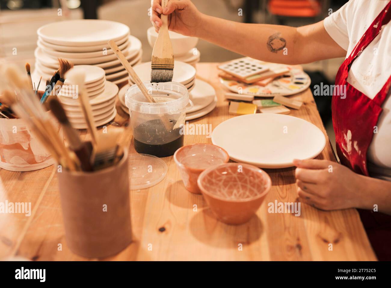Female taking ceramic color paint plate with brush Stock Photo - Alamy