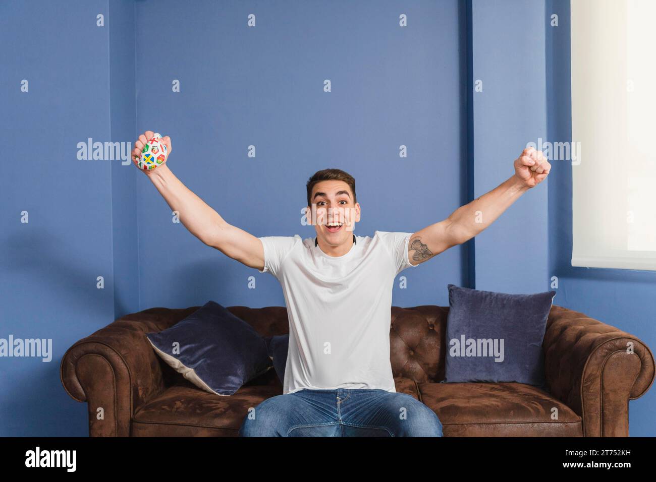 Football fan raising arms couch Stock Photo - Alamy