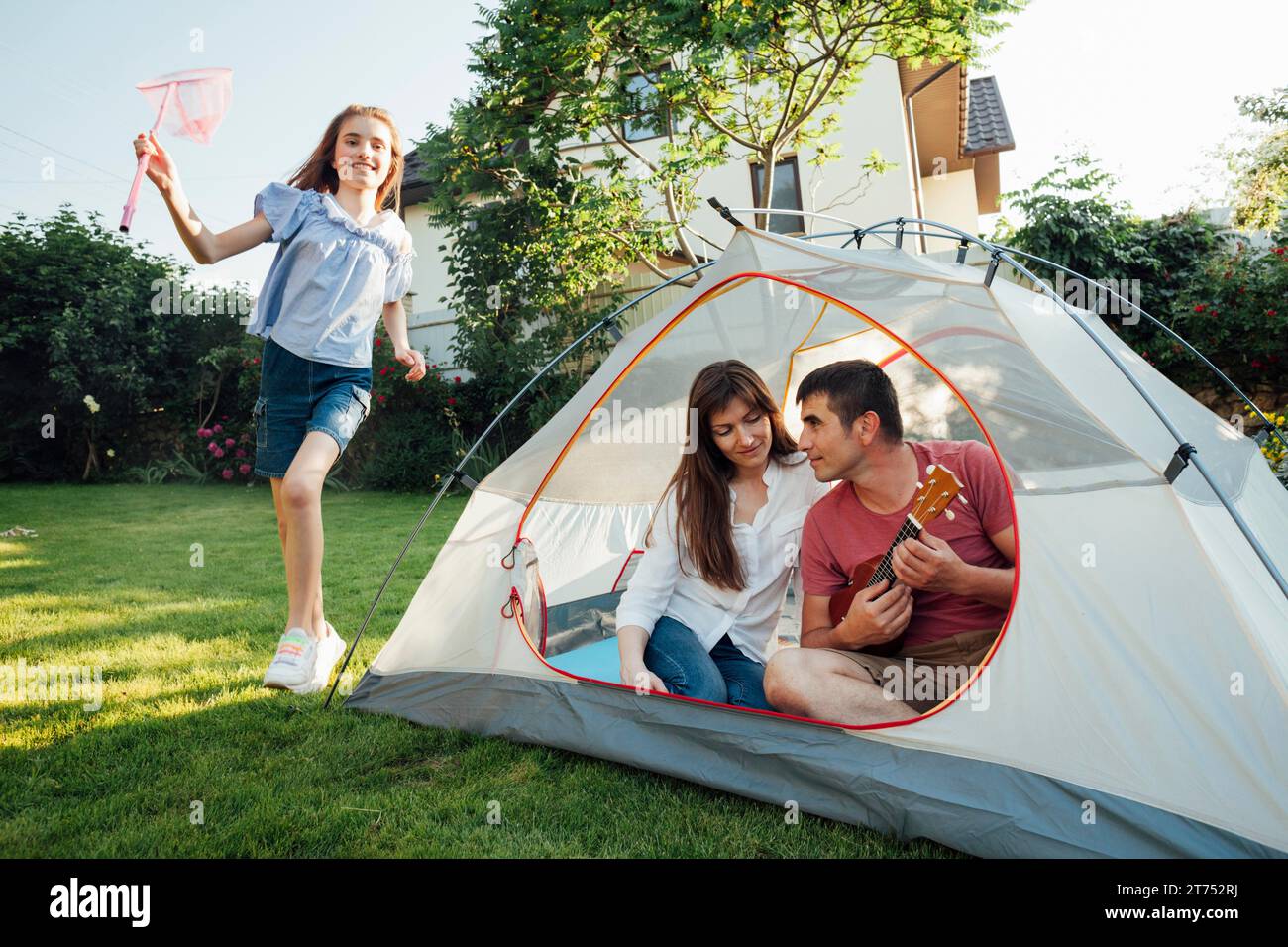 Girl catching butterflies with bug net while her parent sitting net ...
