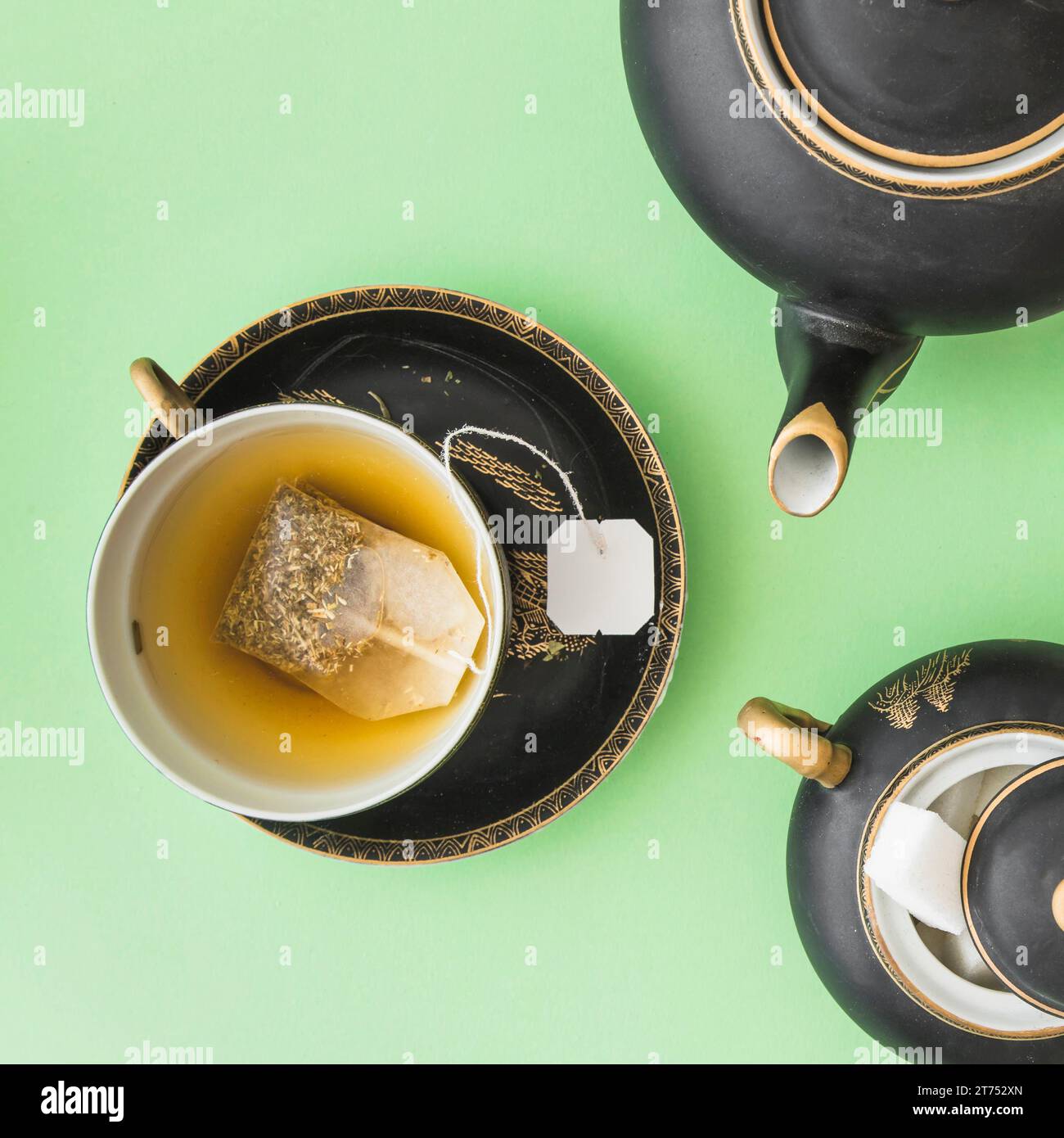 Herbal tea bag cup with teapot sugar cubes green background Stock Photo ...