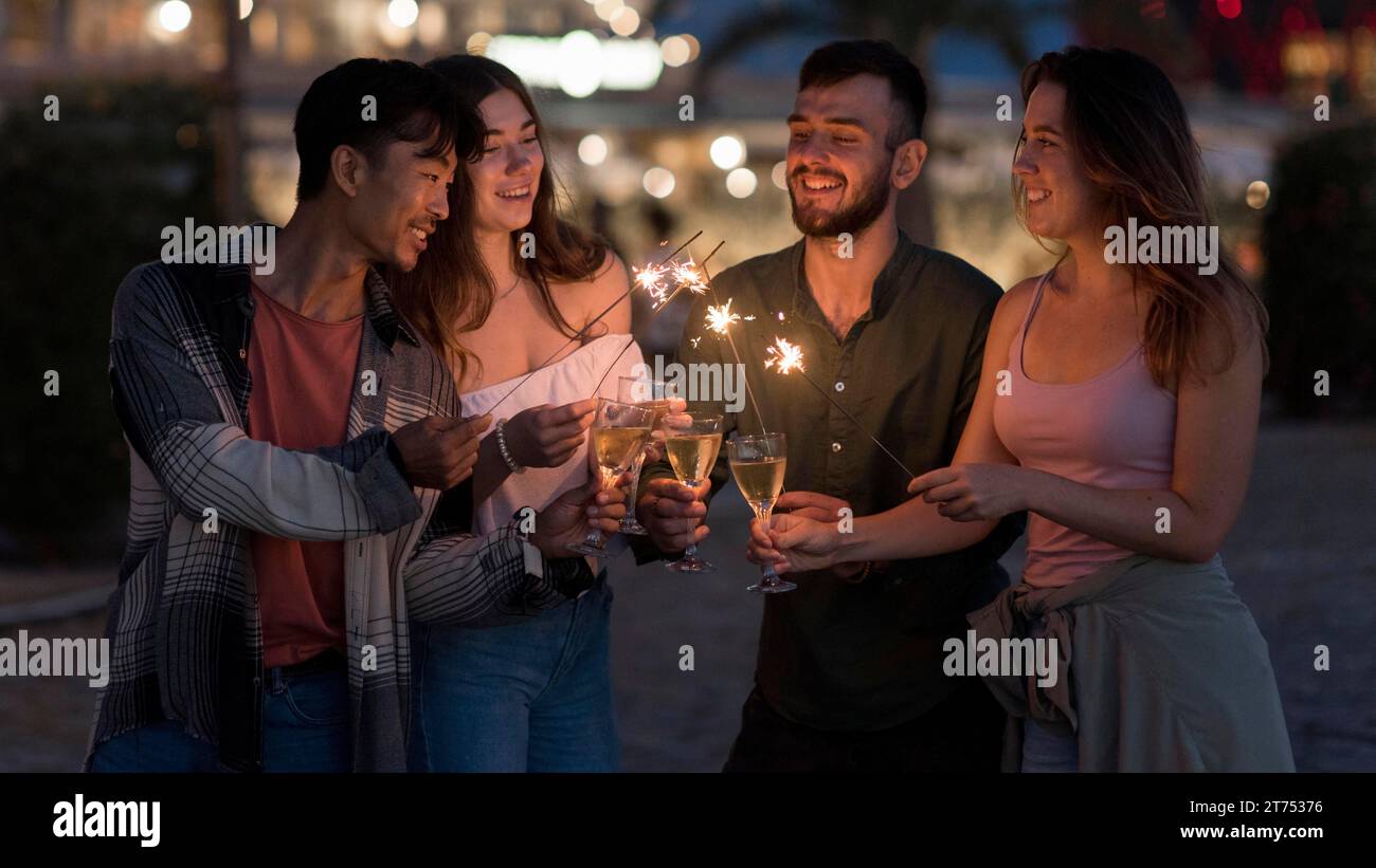 Medium shot friends with fireworks night Stock Photo - Alamy