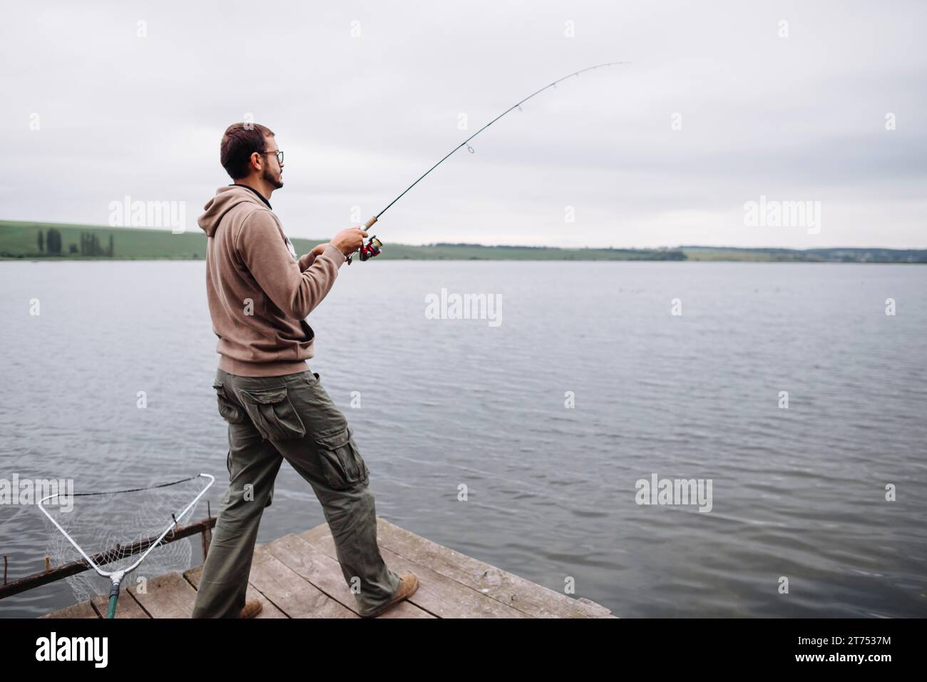 Man standing pier fishing lake Stock Photo - Alamy
