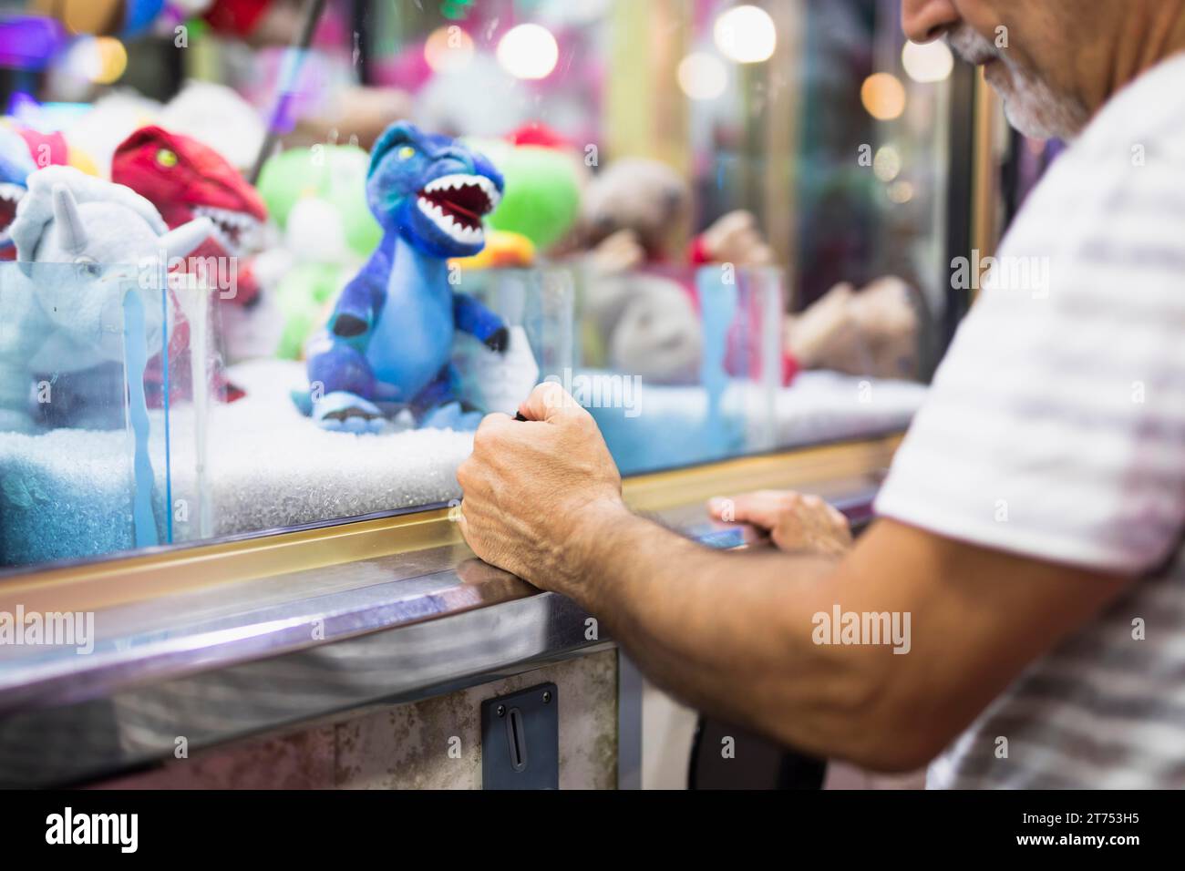 Older man playing toy claw machine Stock Photo - Alamy