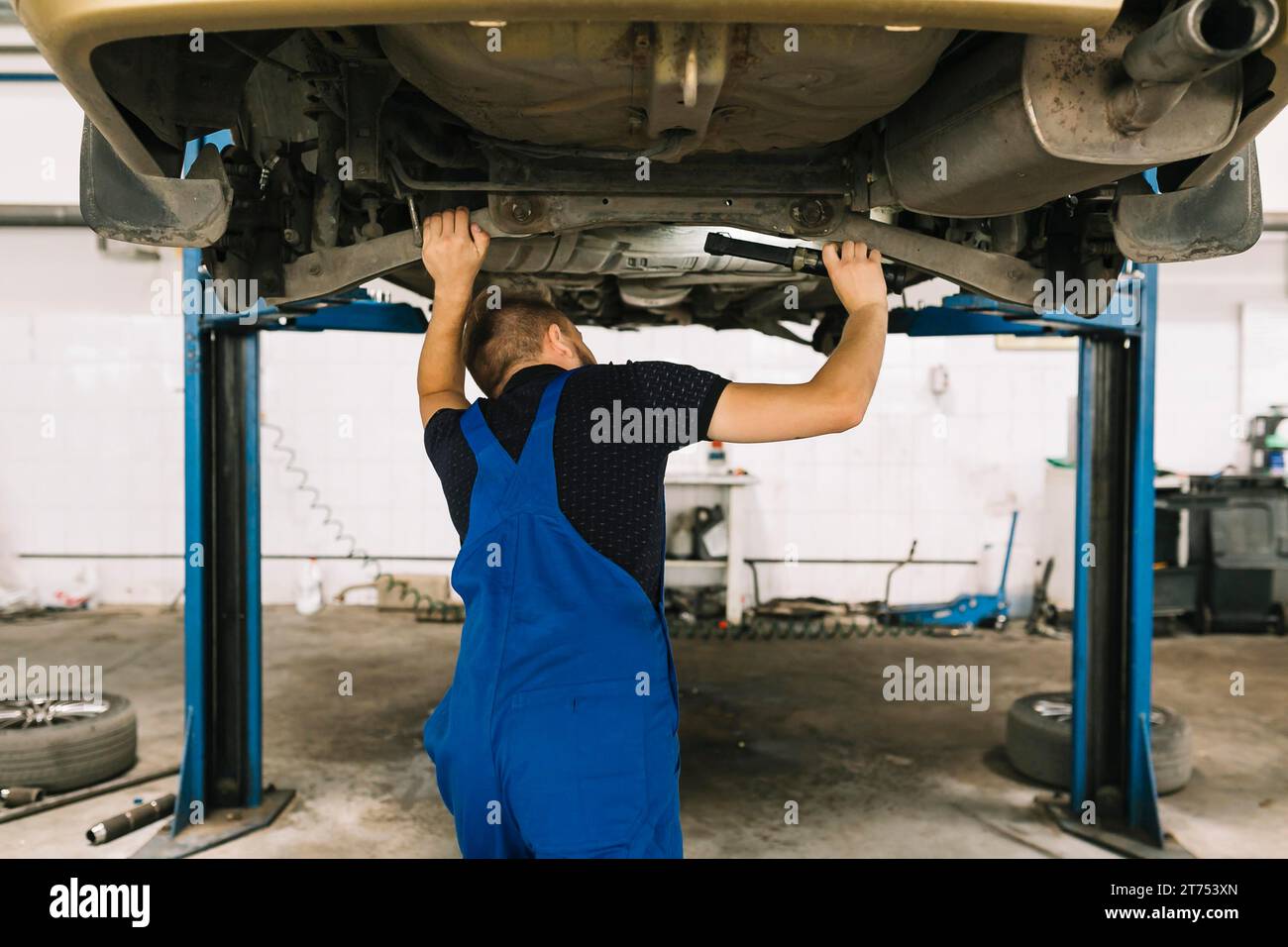 Repairmen examining car bottom Stock Photo - Alamy