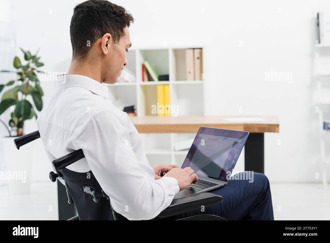 Side view disabled young man sitting wheelchair using laptop office ...