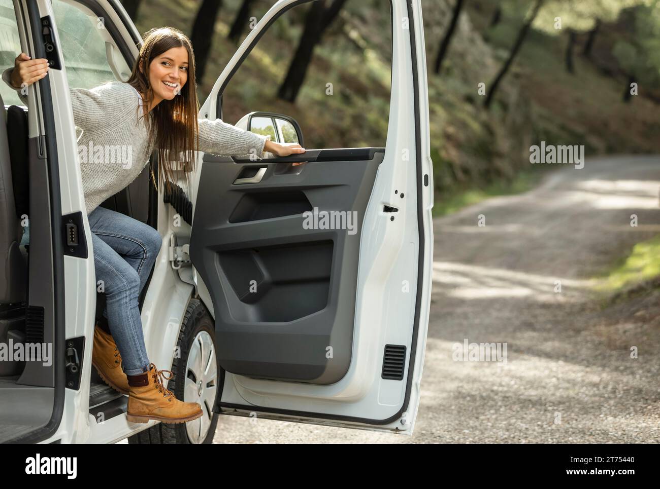 Side view smiley woman getting out car while road trip Stock Photo - Alamy