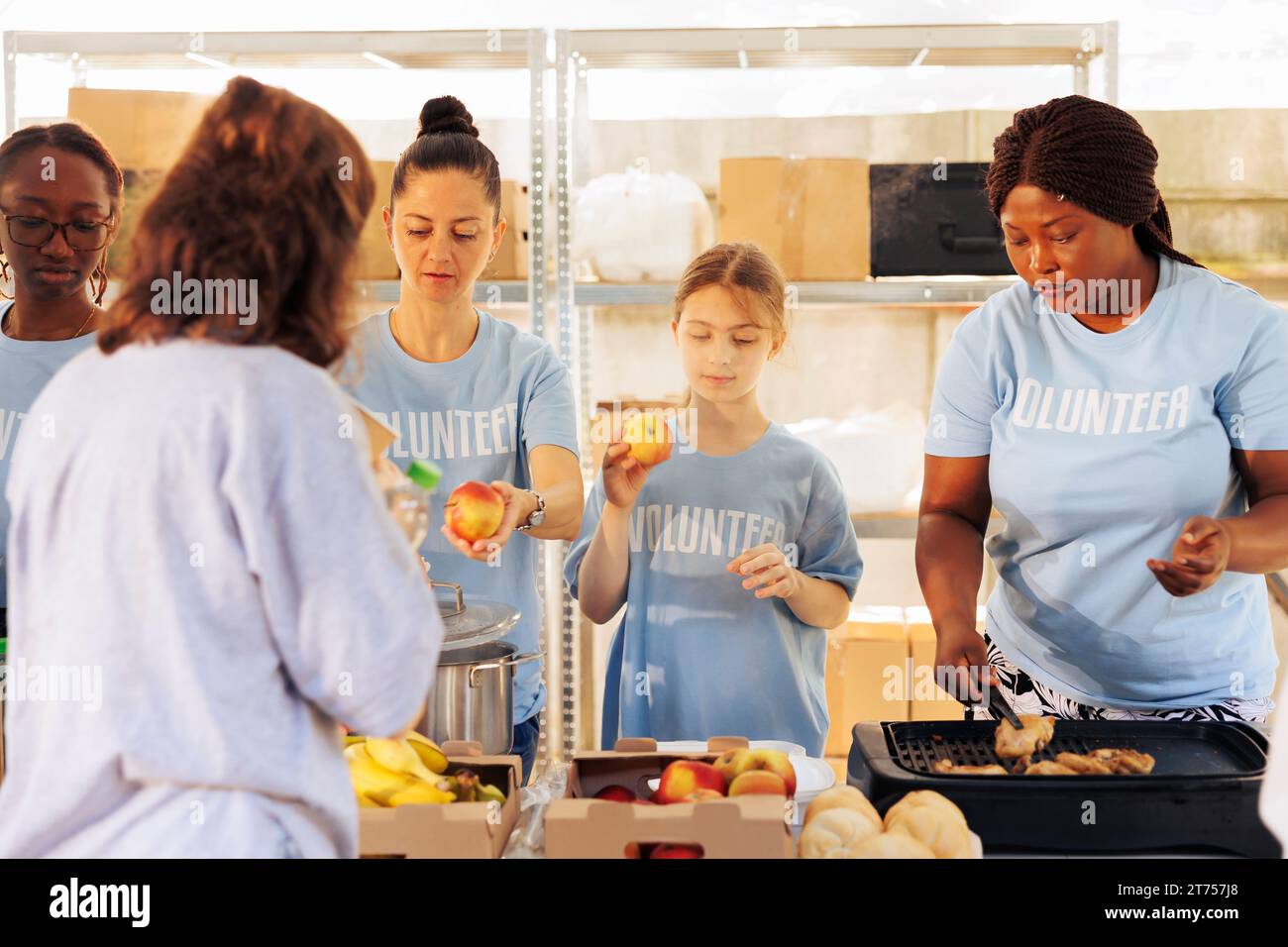 Multiethnic female volunteers sharing fresh fruits and free food to ...